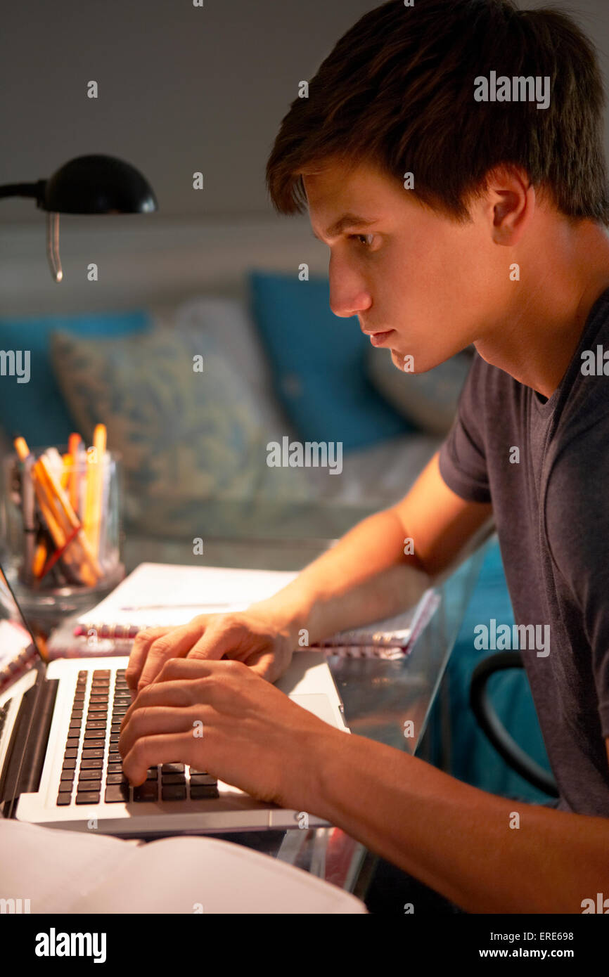 Teenage Boy Studying At Desk In Bedroom In Evening On Laptop Stock ...
