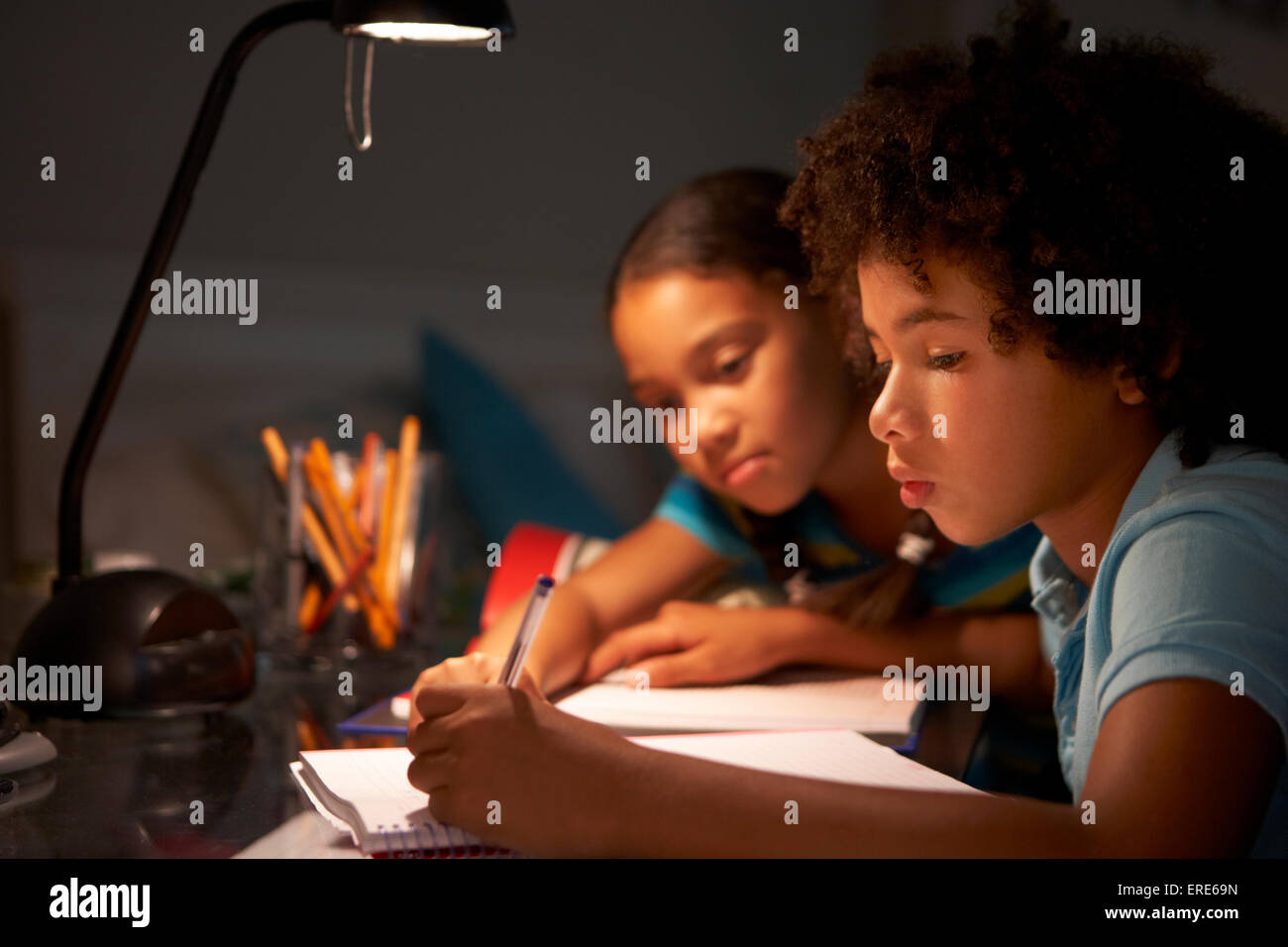 Two Children Studying At Desk In Bedroom In Evening Stock Photo - Alamy