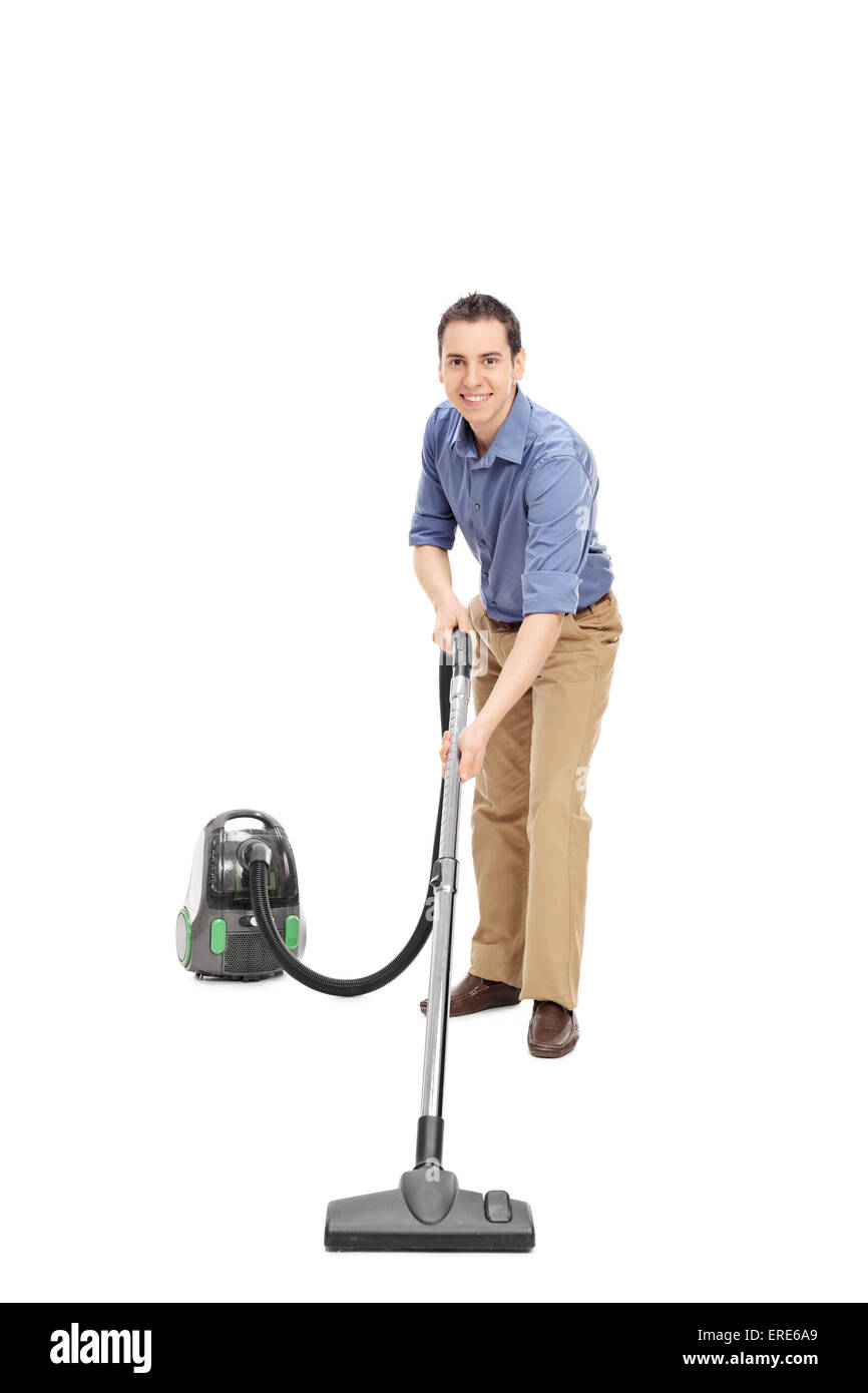 Full length portrait of a young man cleaning with a vacuum cleaner and ...