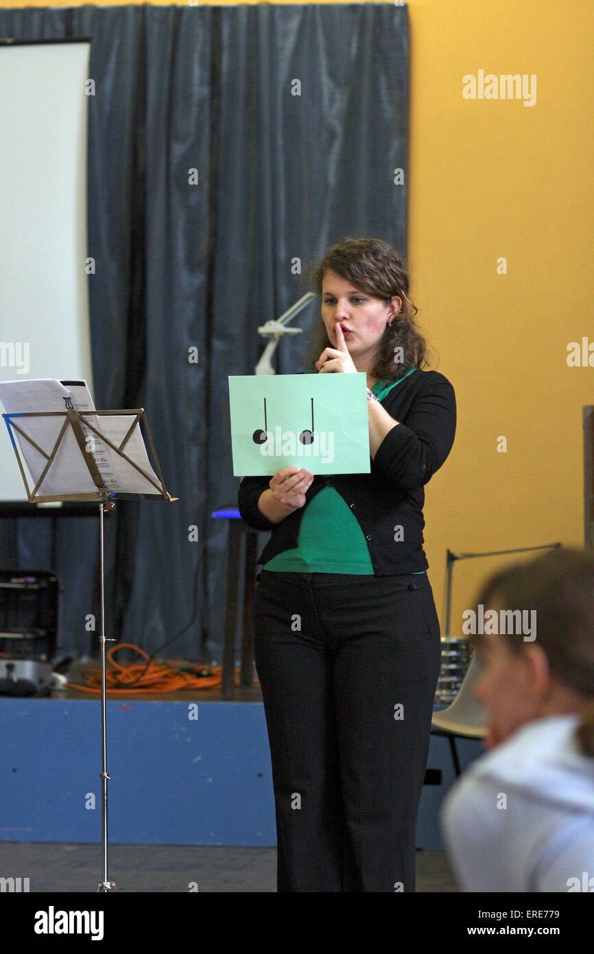 Music teacher in a music classroom, workshop holding up a rhythm on a ...