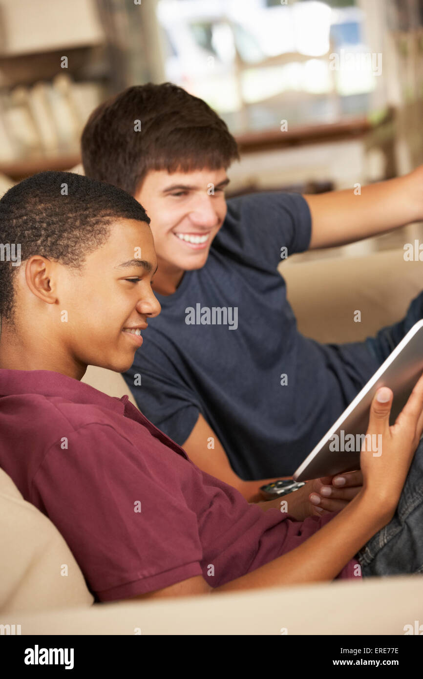 Two Teenage Boys Sitting On Sofa At Home Using Tablet Computer Stock ...