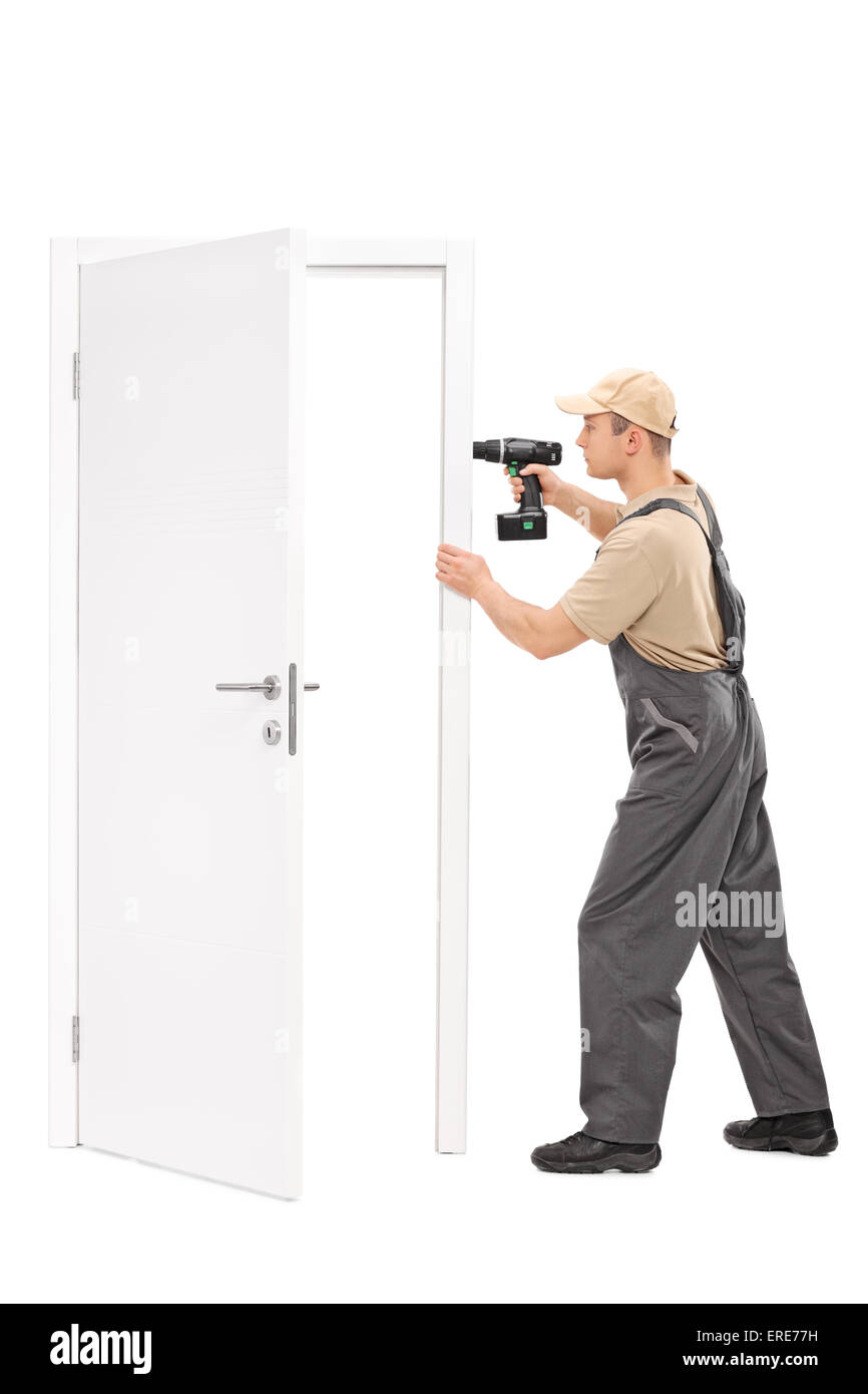 Full length portrait of a young manual worker installing a door with a ...