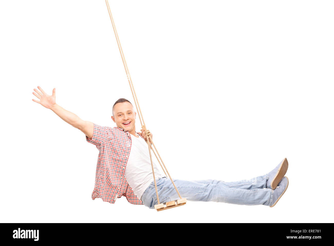 Studio shot of a young joyful man swinging on a swing and gesturing ...