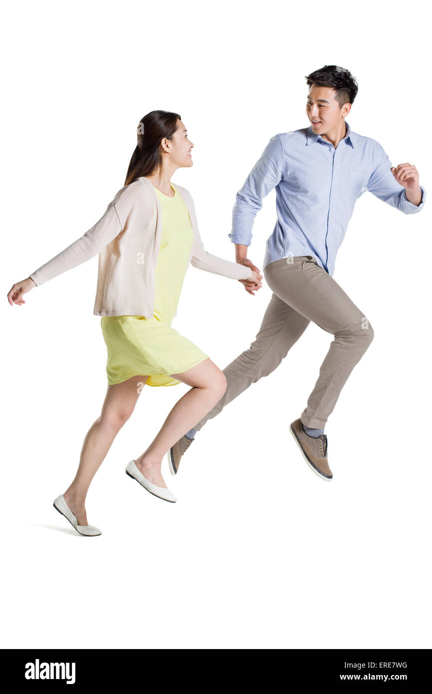 Happy young couple holding hands running Stock Photo - Alamy