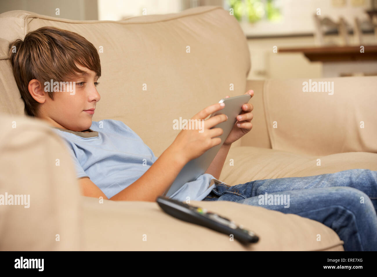Young Boy Sitting On Sofa At Home Using Tablet Computer Stock Photo - Alamy