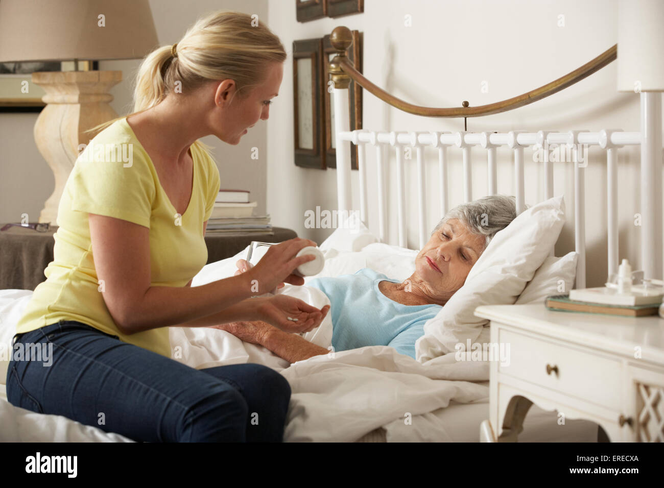 Adult Daughter Giving Senior Female Parent Medication In Bed At Home ...