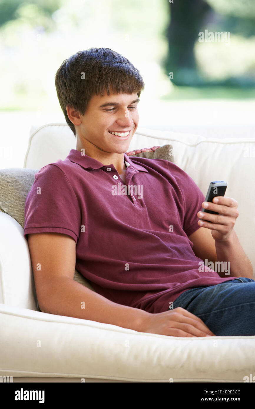 Teenage Boy Sending Text Message Sitting On Sofa Stock Photo - Alamy