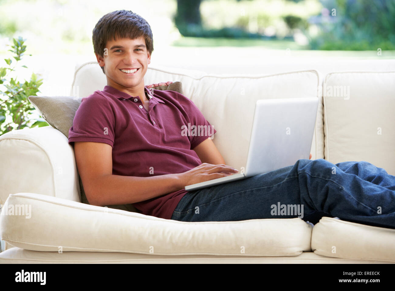 Teenage Boy Relaxing On Sofa At Home Using Laptop Stock Photo - Alamy