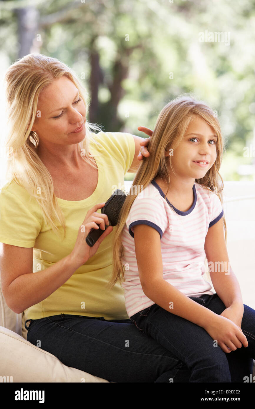 Mother Brushing Daughters Hair On Sofa At Home Stock Photo - Alamy