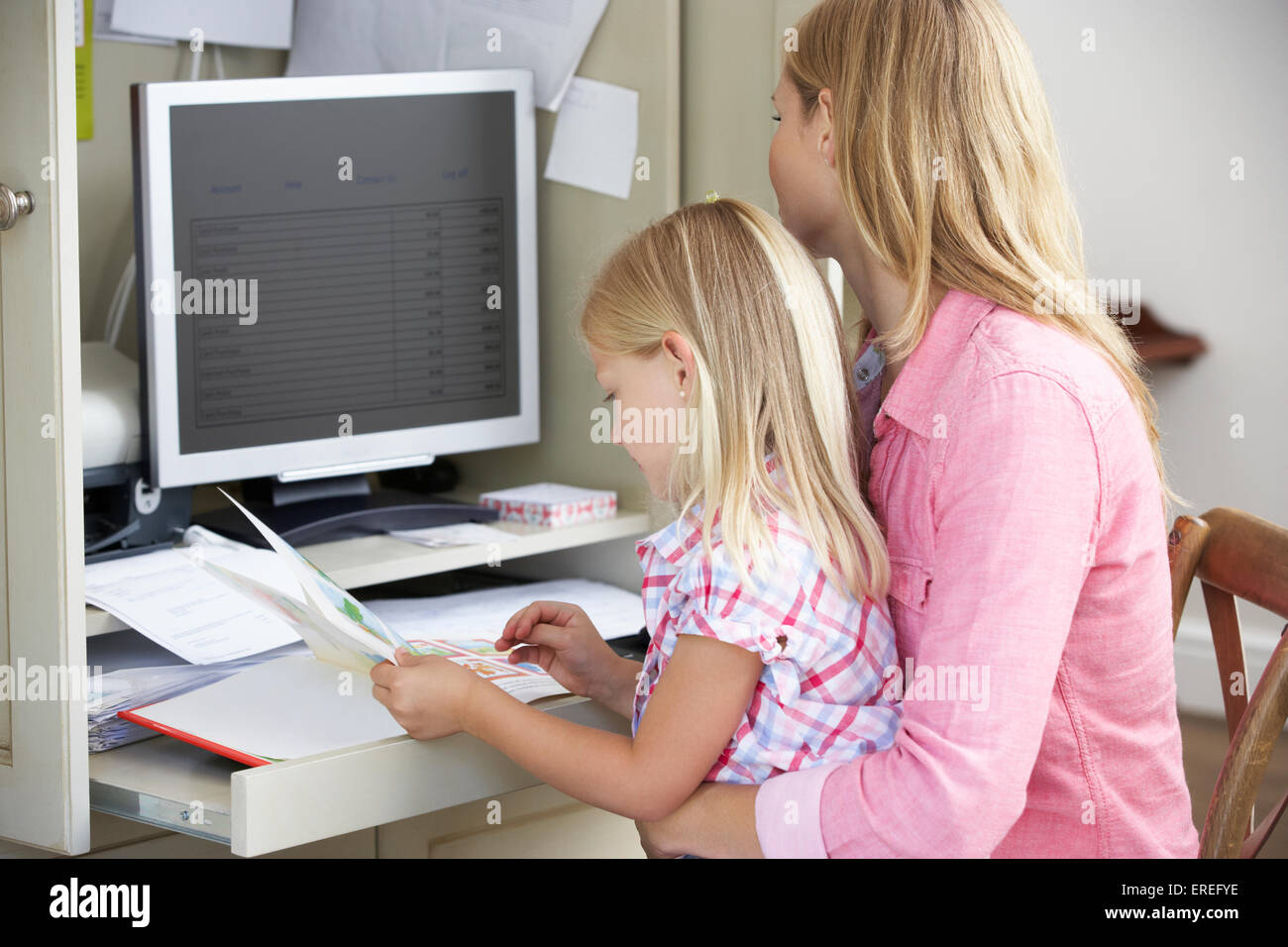 Daughter Reading Book Whilst Mother Works In Home Office Stock Photo ...