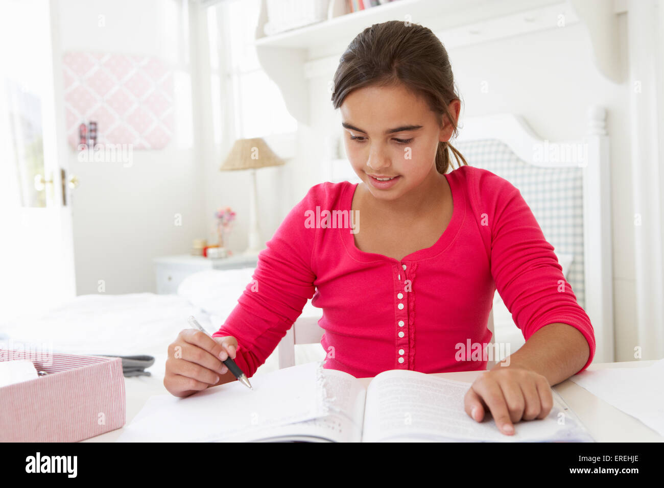 Young Girl Doing Homework At Desk In Bedroom Stock Photo - Alamy
