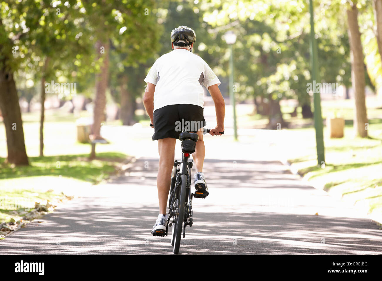 Rear View Of Mature Man Cycling Through Park Stock Photo - Alamy