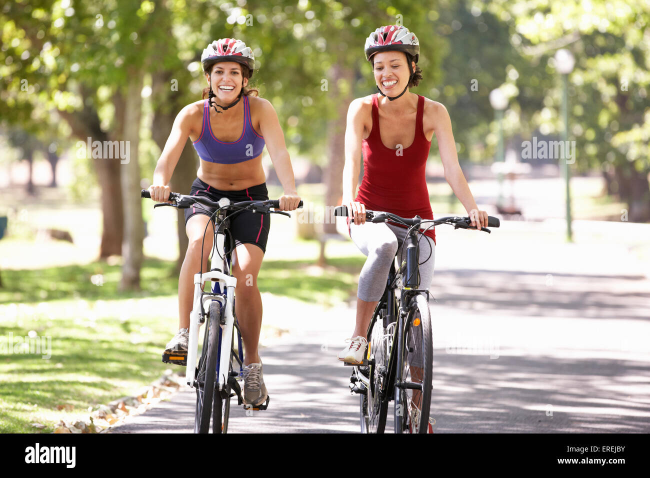 Two Women Cycling Through Park Stock Photo - Alamy