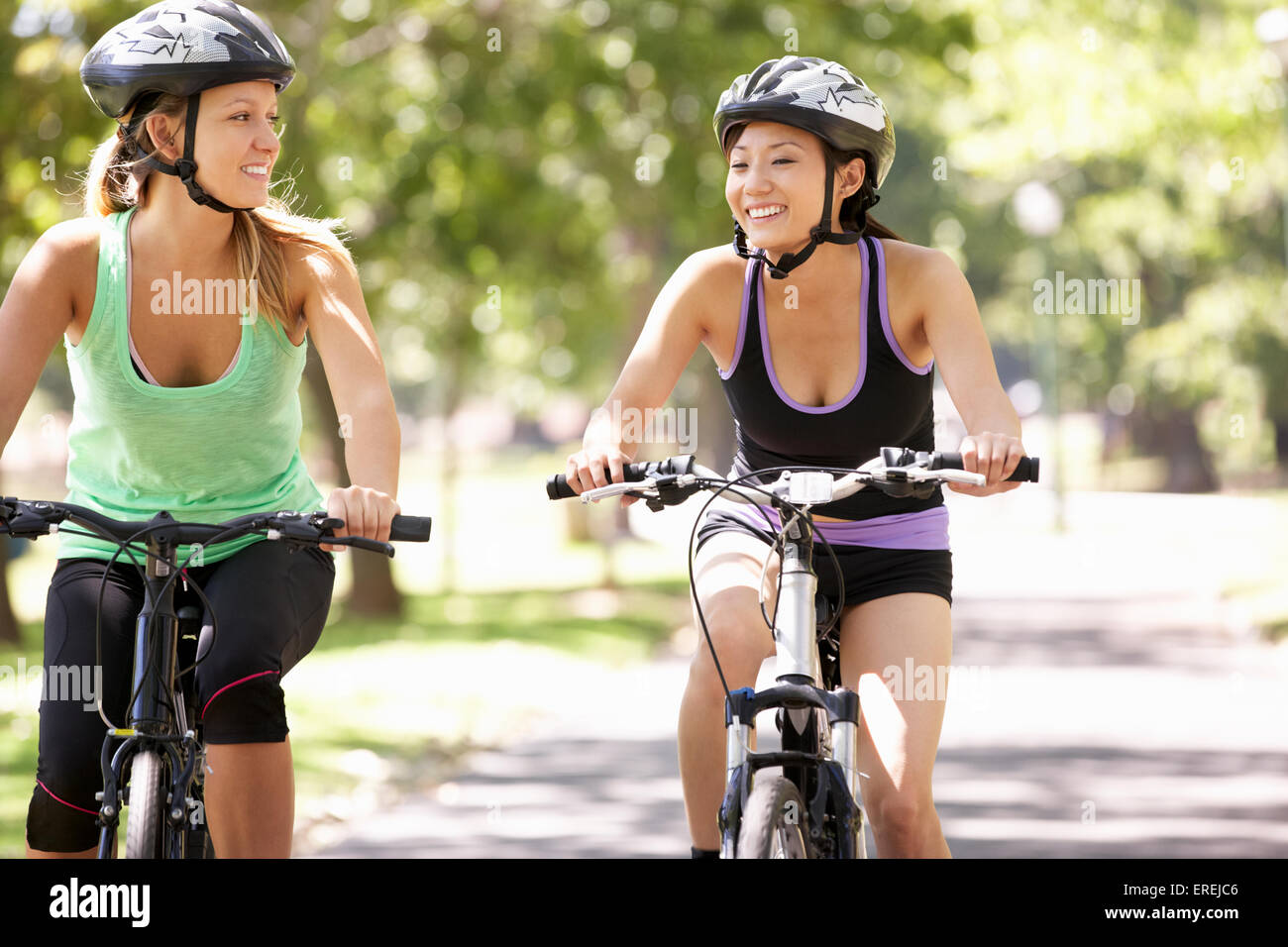 Two Women Cycling Through Park Stock Photo - Alamy