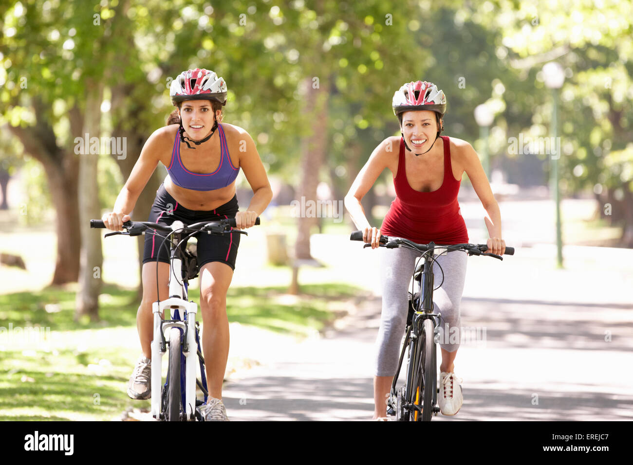 Two Women Cycling Through Park Stock Photo - Alamy