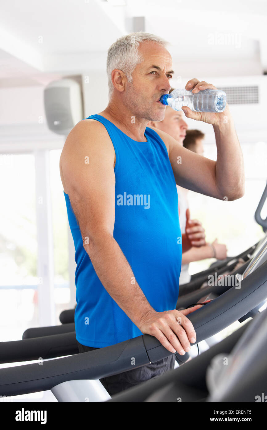 Man On Running Machine In Gym Drinking Water Stock Photo - Alamy