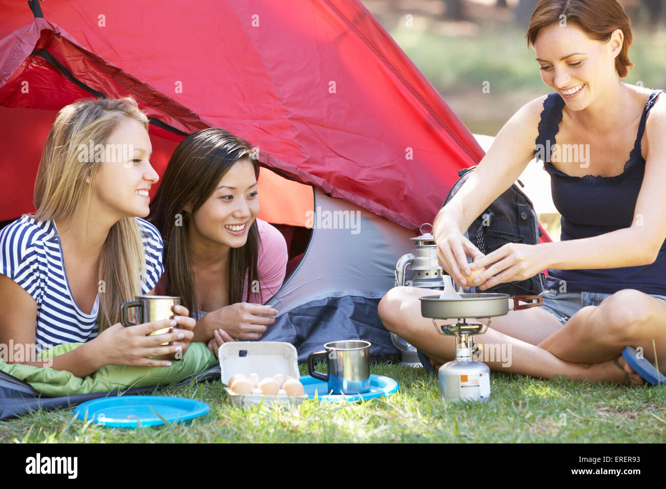 Three Young Women Cooking On Camping Stove Outside Tent Stock Photo - Alamy