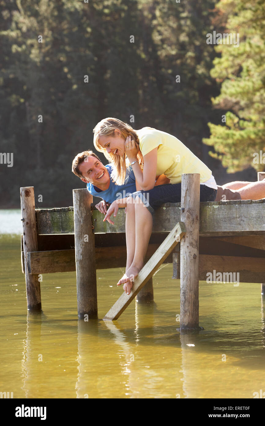 Romantic Couple Sitting On Wooden Jetty Looking Out Over Lake Stock ...