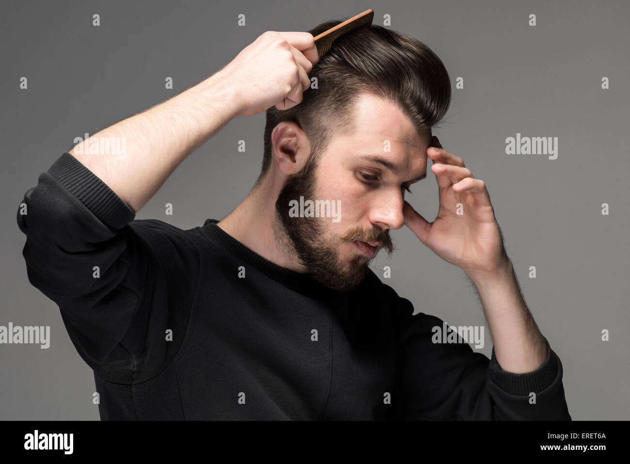 young man comb his hair on gray background Stock Photo - Alamy