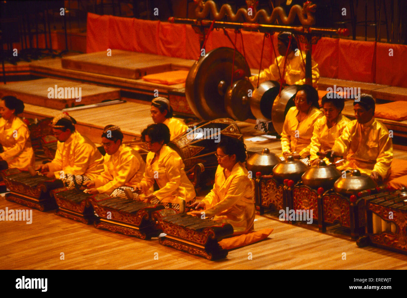 Indonesian musicians in yellow costumes playing gamelan instruments ...