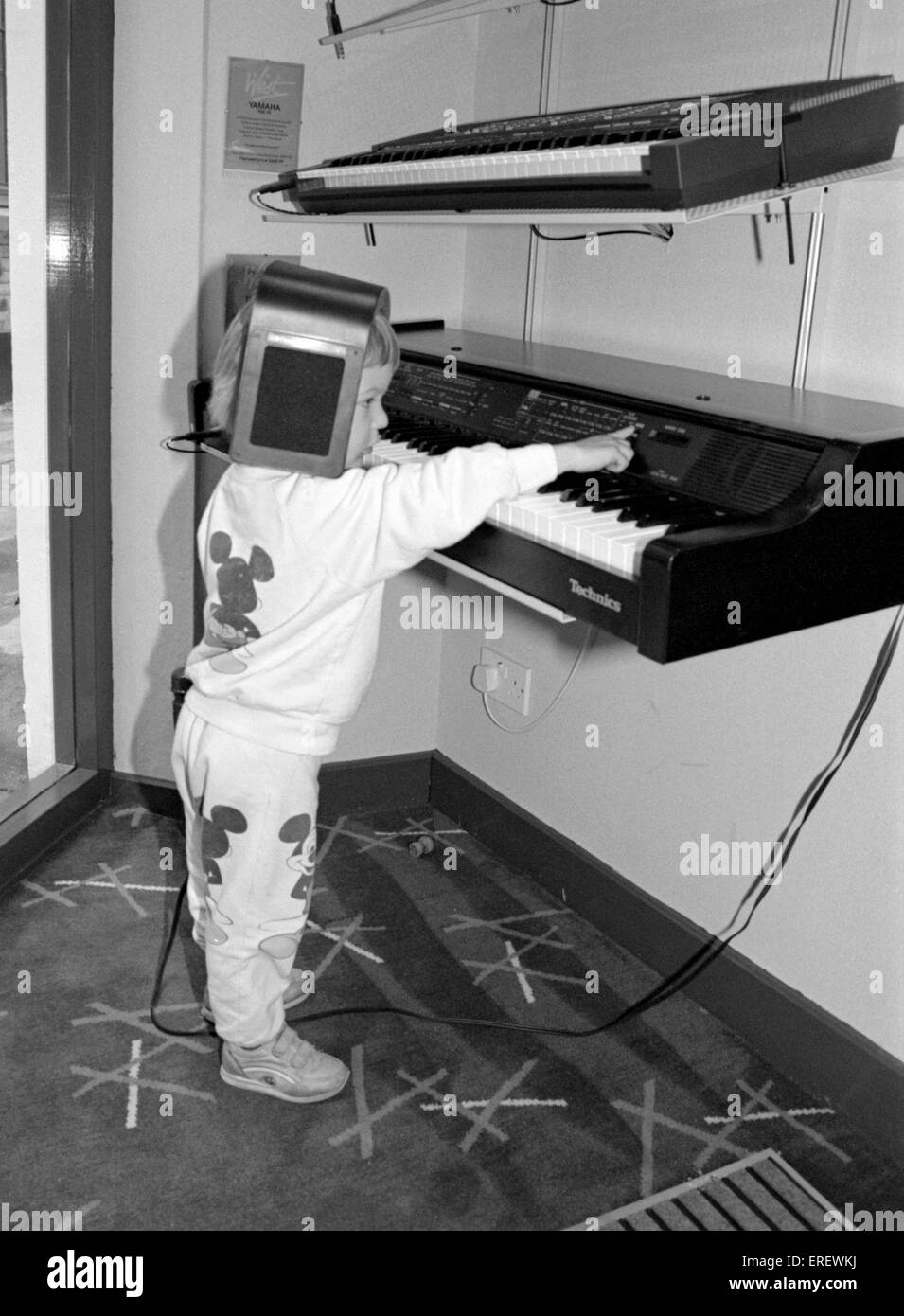 Very young child wearing large headphones, pushing a button on an ...