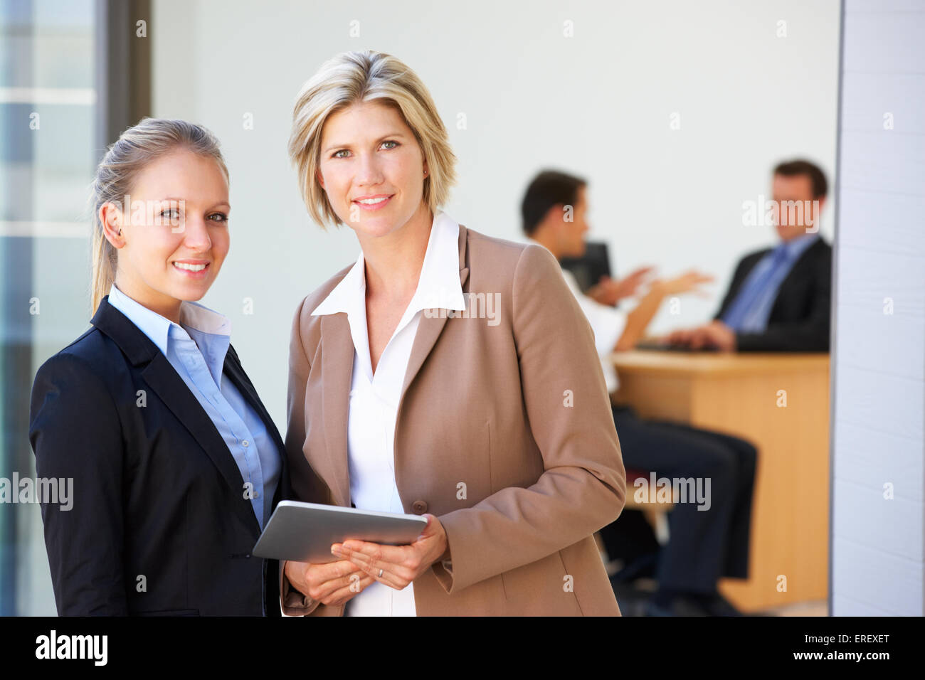Two Female Executives Using Tablet Computer With Office Meeting In ...