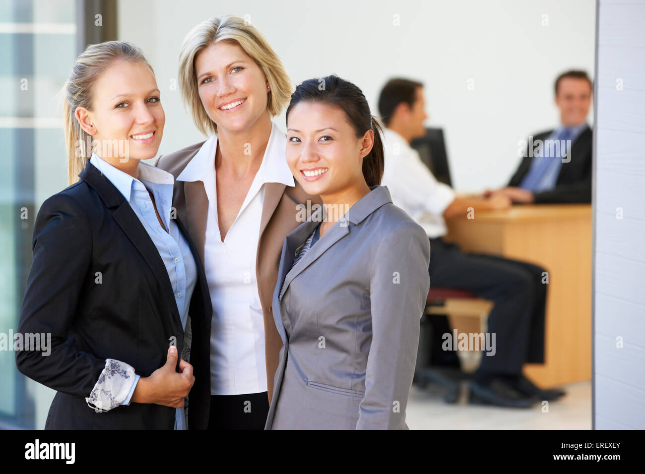 Portrait Of Three Female Executives With Office Meeting In Background ...