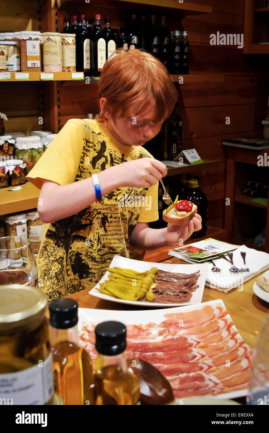 Young boy helps himself to Pintox tapas in a bar in San Sebastion ...
