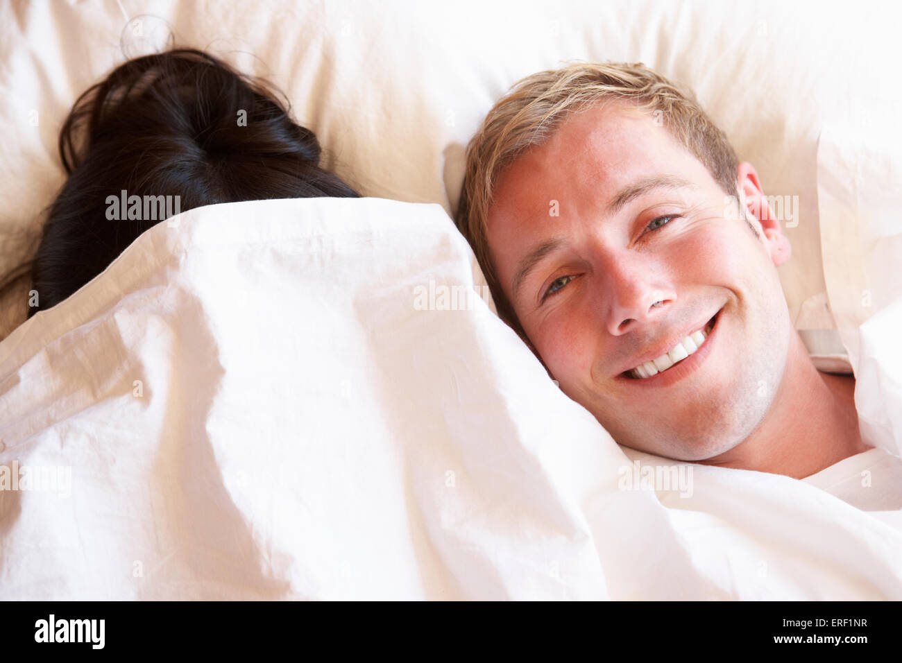 Couple Relaxing In Bed Hiding Under Bedclothes Stock Photo - Alamy