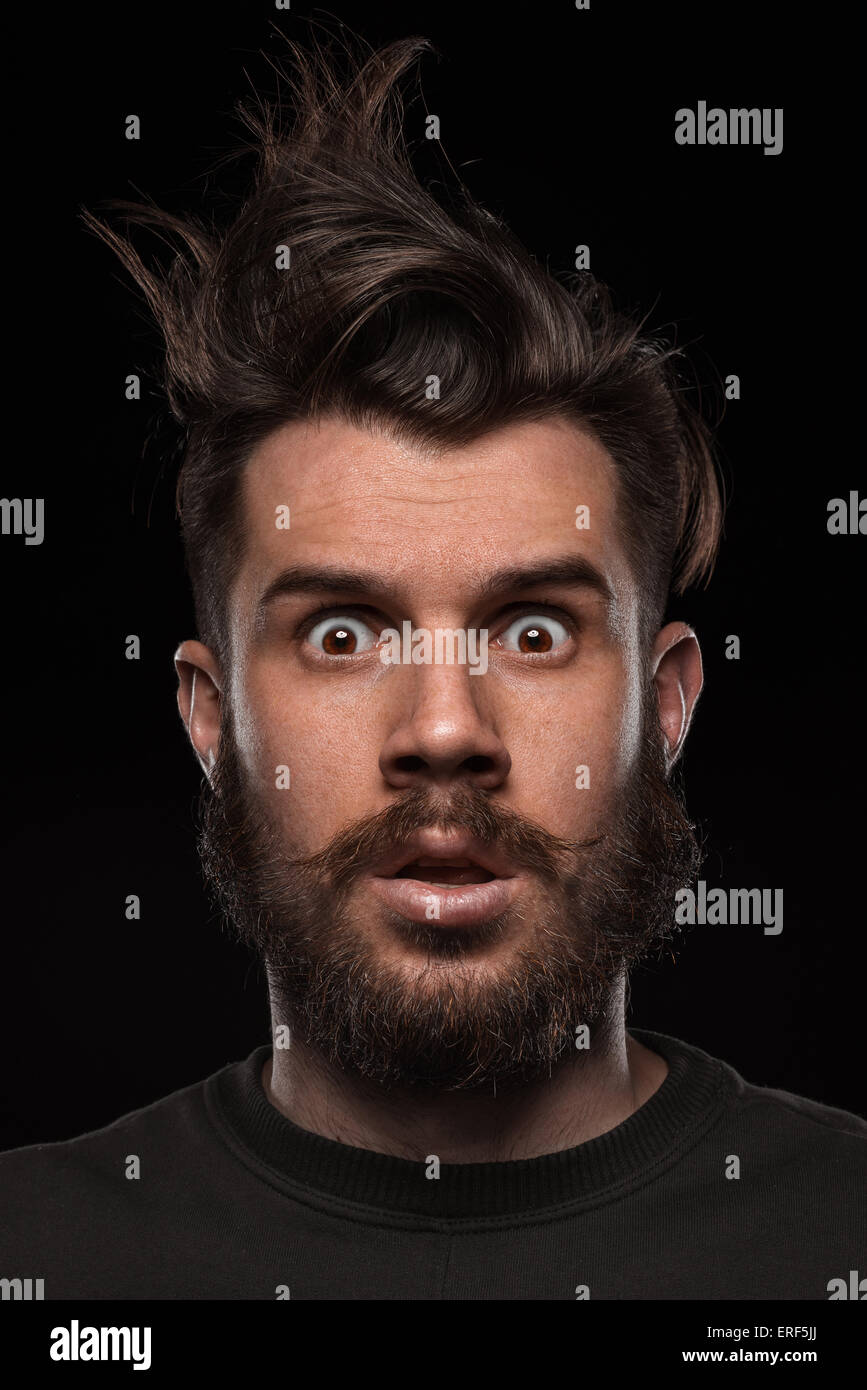 Portrait of young frightened man with a beard and mustache in studio on ...