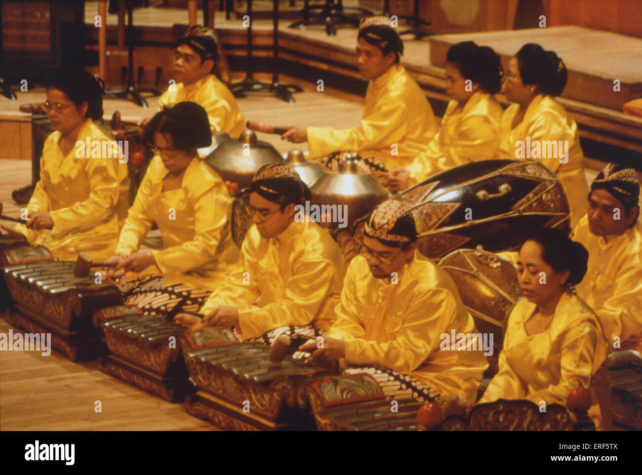 Musicians in yellow costumes playing gamelan instruments at performance ...