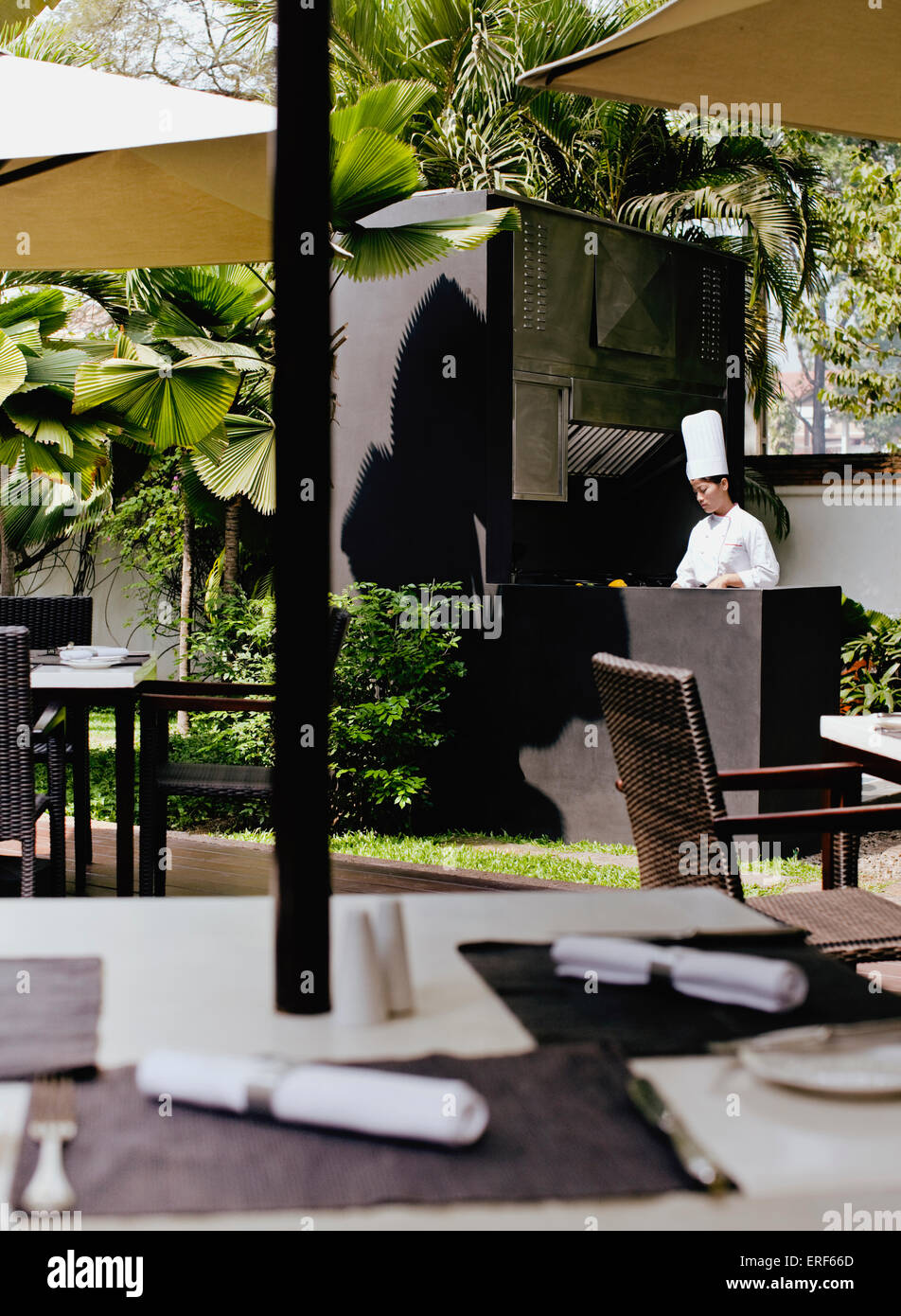 Young Asian female chef behind the grill at the Poolside BBQ restaurant ...