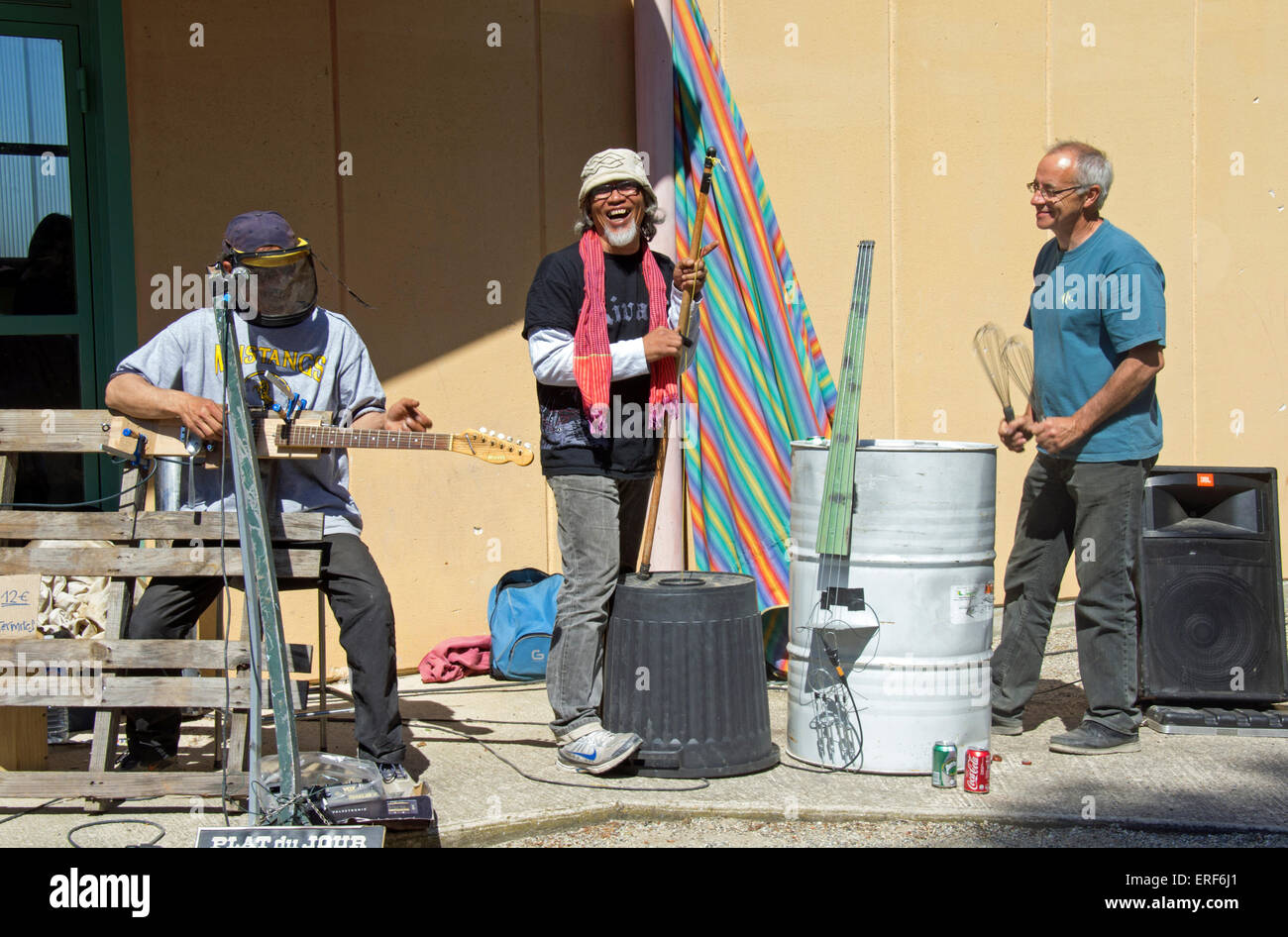 Three musicians playing instruments made up of recycled materials ...
