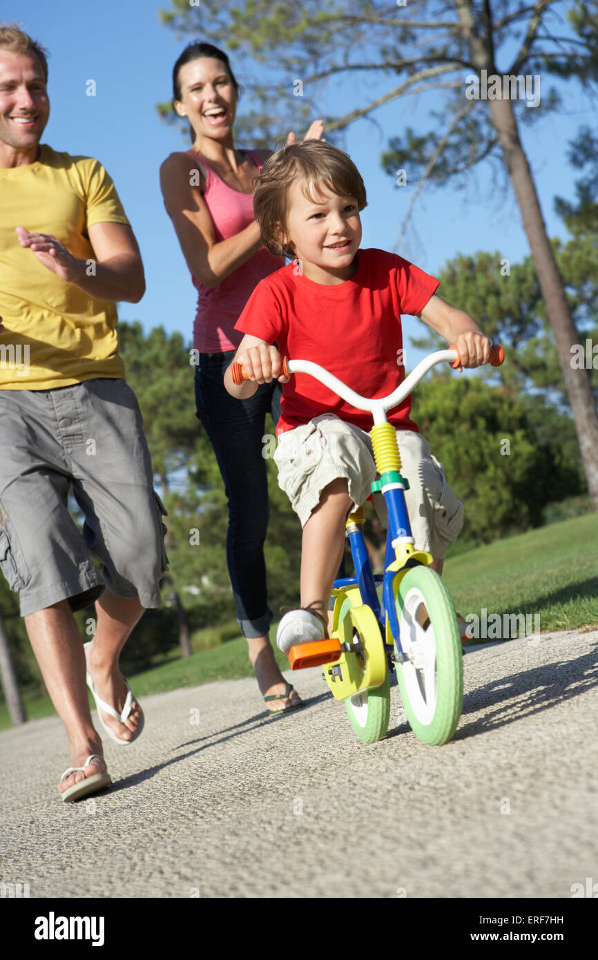 Parents Teaching Son To Ride Bike In Park Stock Photo - Alamy