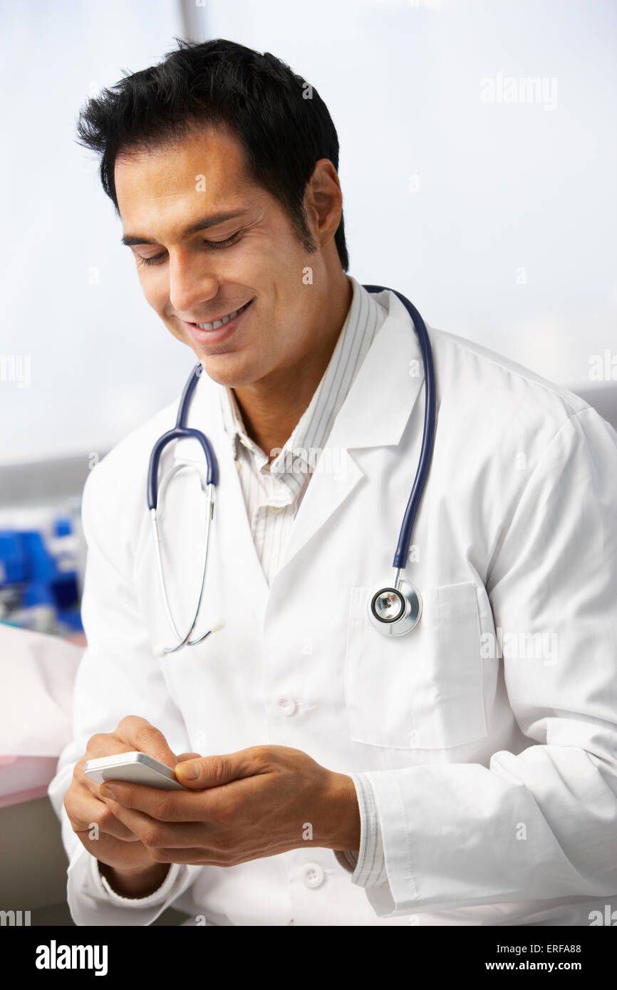 Male Doctor In Surgery Using Mobile Phone Stock Photo - Alamy