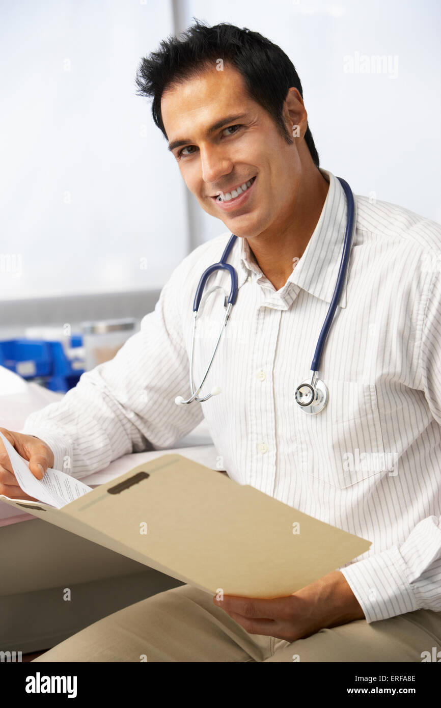 Male Doctor In Surgery Reading Patient Notes Stock Photo - Alamy