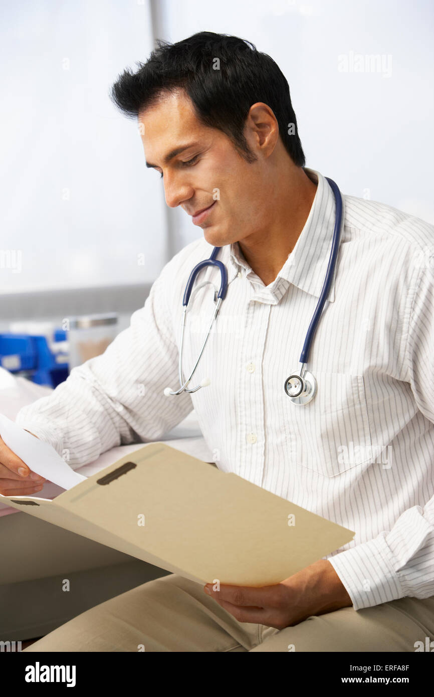 Male Doctor In Surgery Reading Patient Notes Stock Photo - Alamy