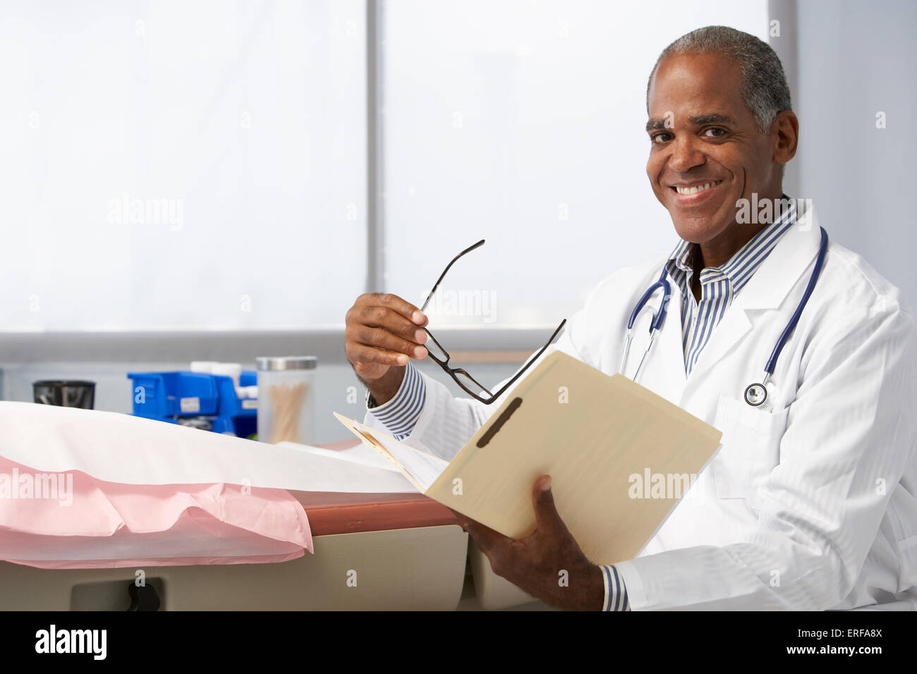 Male Doctor In Surgery Reading Patient Notes Stock Photo - Alamy