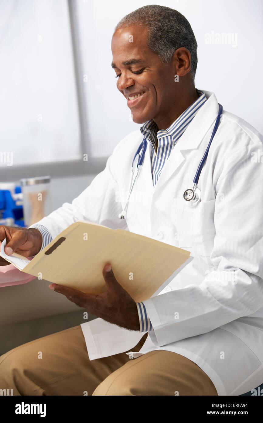 Male Doctor In Surgery Reading Patient Notes Stock Photo - Alamy