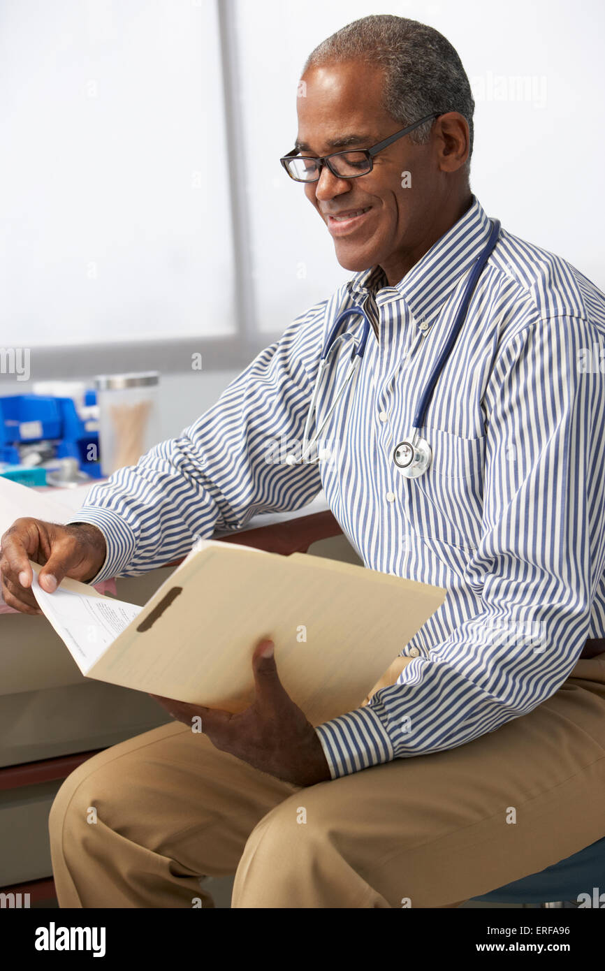 Male Doctor In Surgery Reading Patient Notes Stock Photo - Alamy