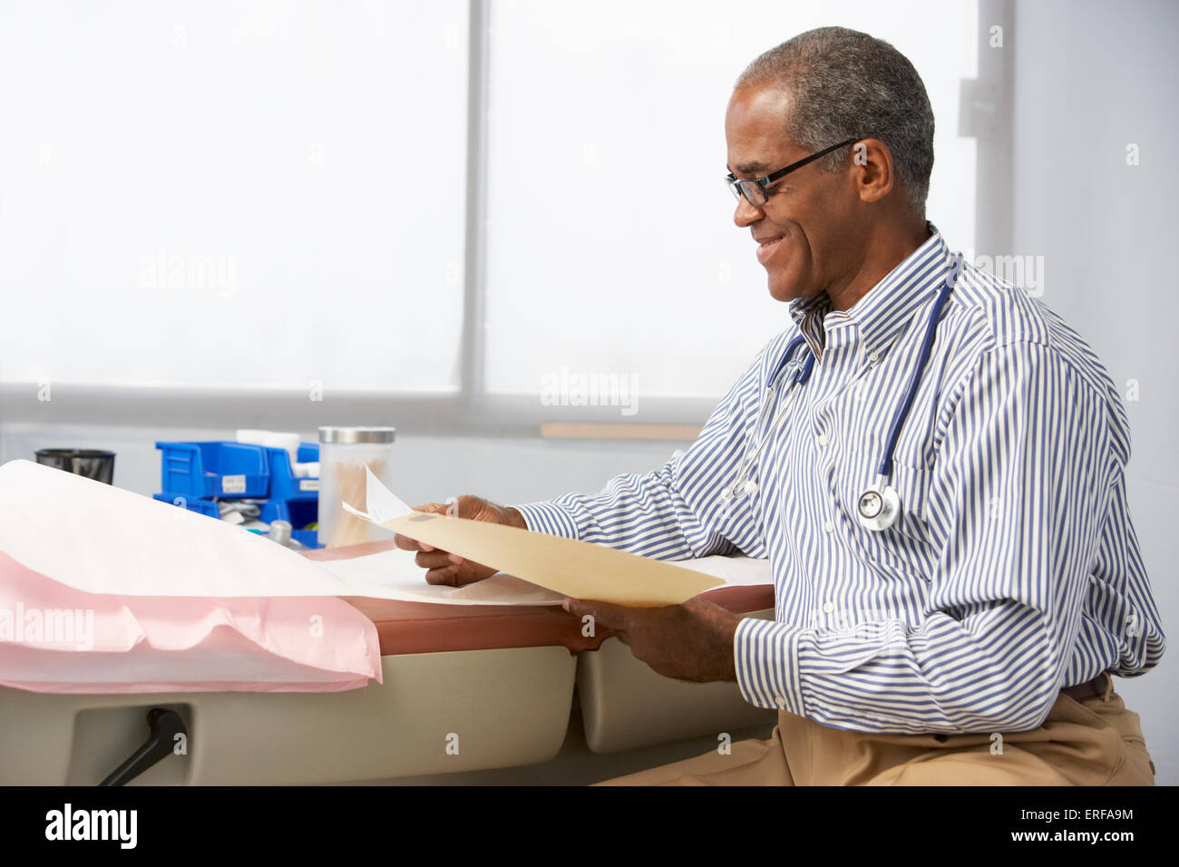 Male Doctor In Surgery Reading Patient Notes Stock Photo - Alamy