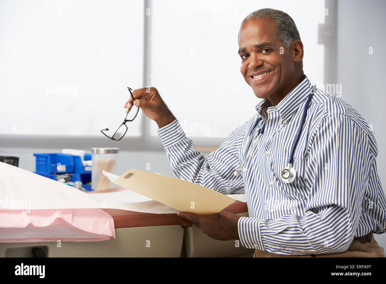 Male Doctor In Surgery Reading Patient Notes Stock Photo - Alamy