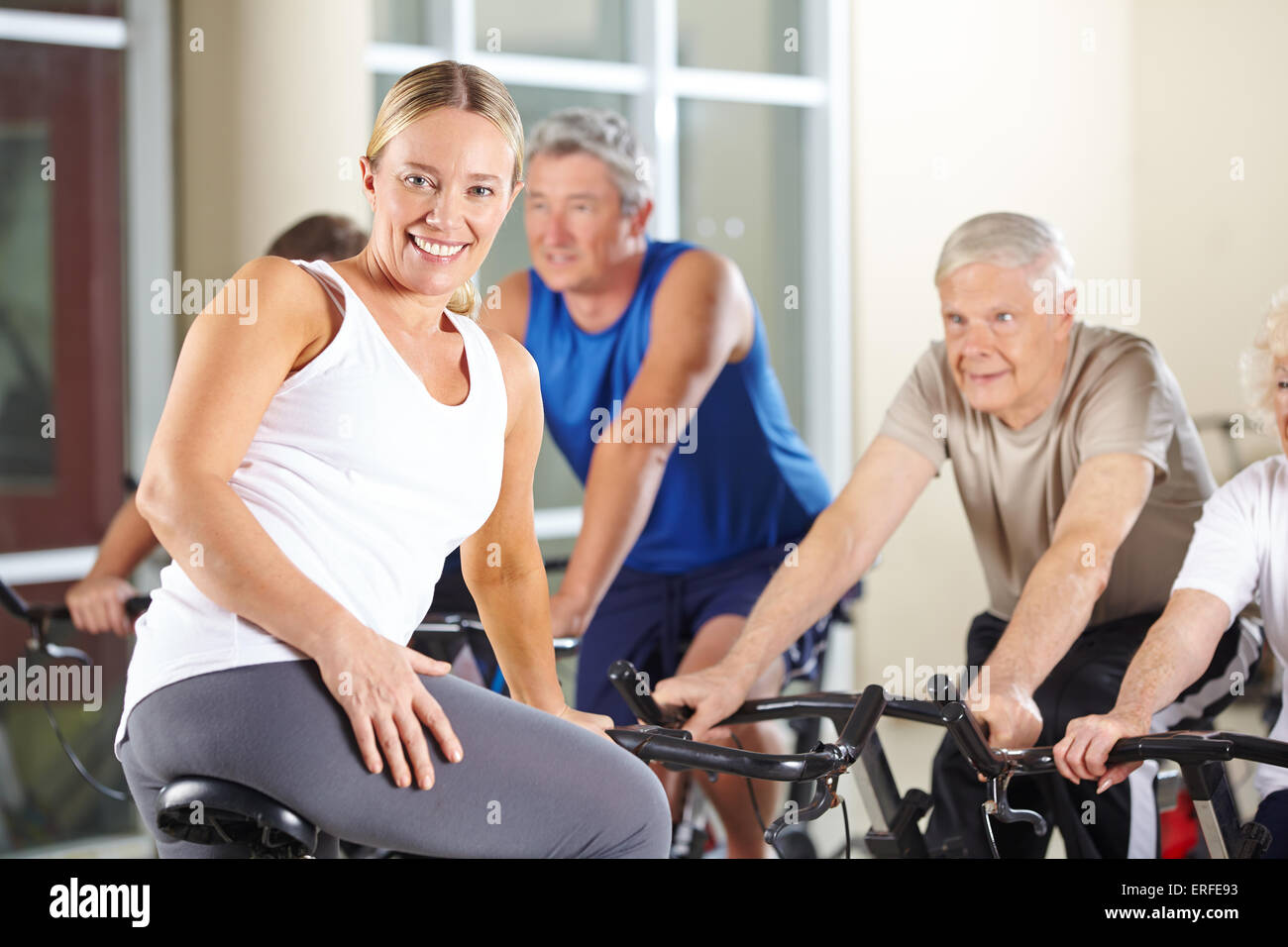 Senior people in spinning class in gym with smiling female fitness ...