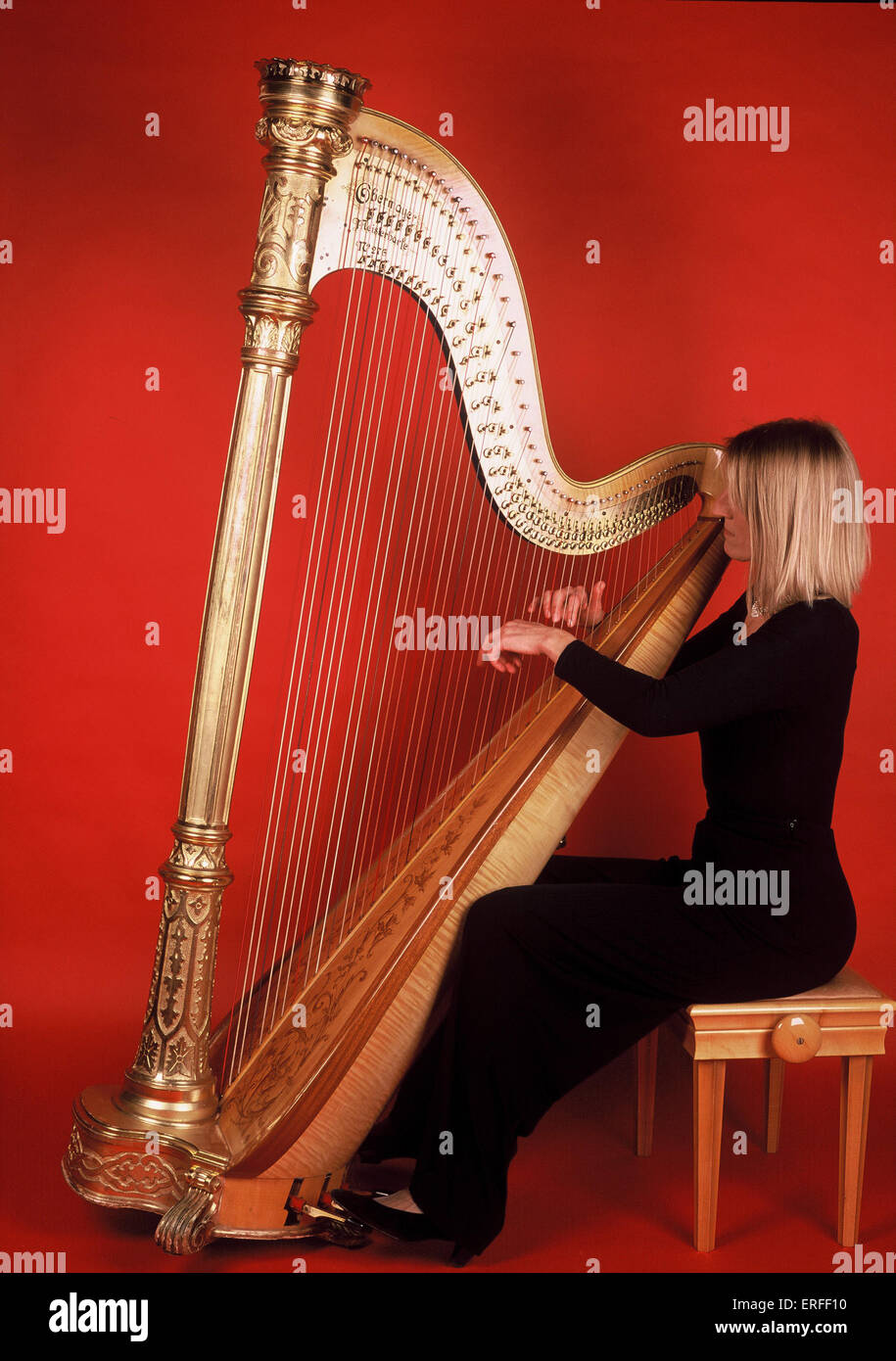 Female playing the harp. Red background Stock Photo - Alamy