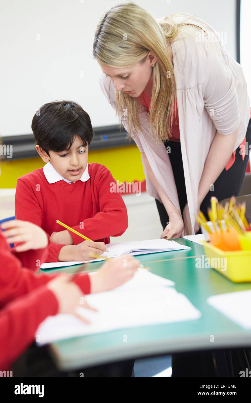 Teacher Helping Male Pupil With Written Work At Desk Stock Photo - Alamy