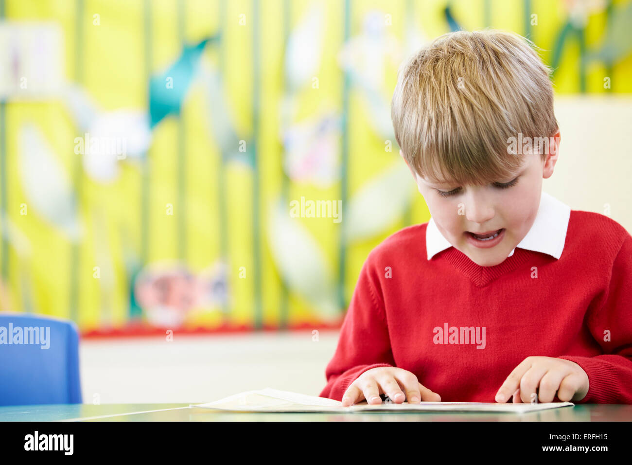 Male Pupil Reading Book At Table Stock Photo - Alamy