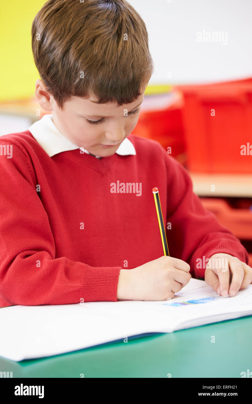 Male Pupil Practising Writing At Table Stock Photo - Alamy