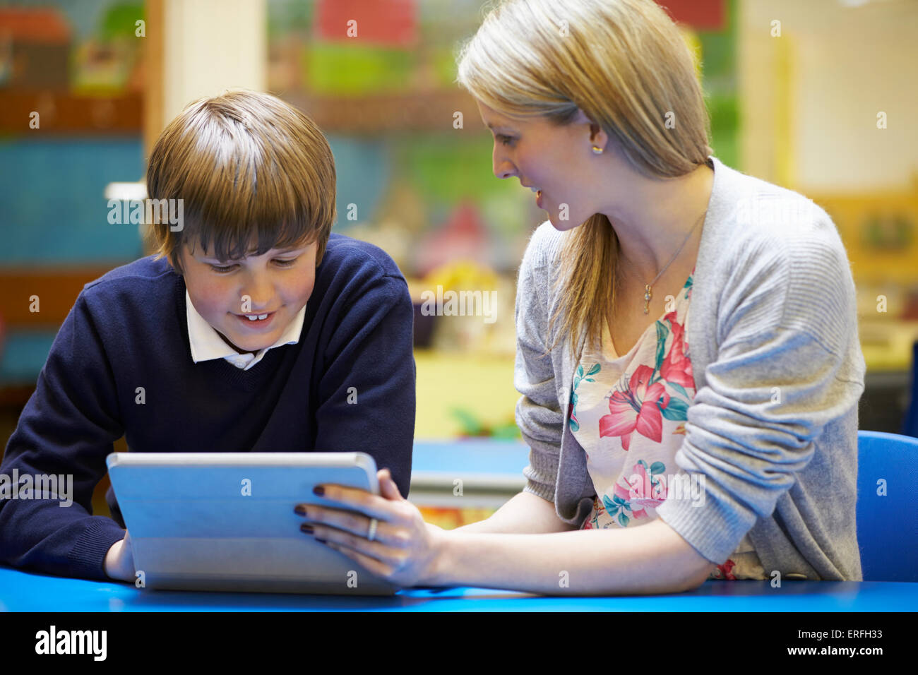 Teacher With Male Pupil Using Digital Tablet In Classroom Stock Photo ...