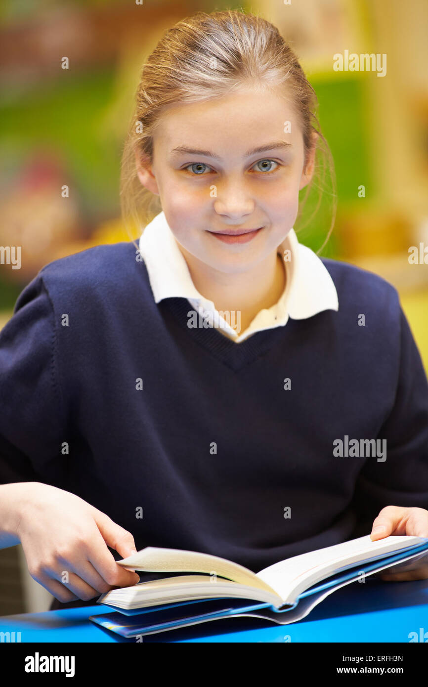 Female Elementary School Pupil Reading Book In Classroom Stock Photo ...
