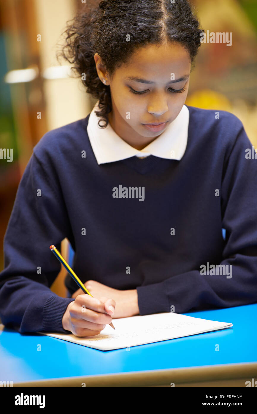 Female Elementary School Pupil Writing Book In Classroom Stock Photo ...